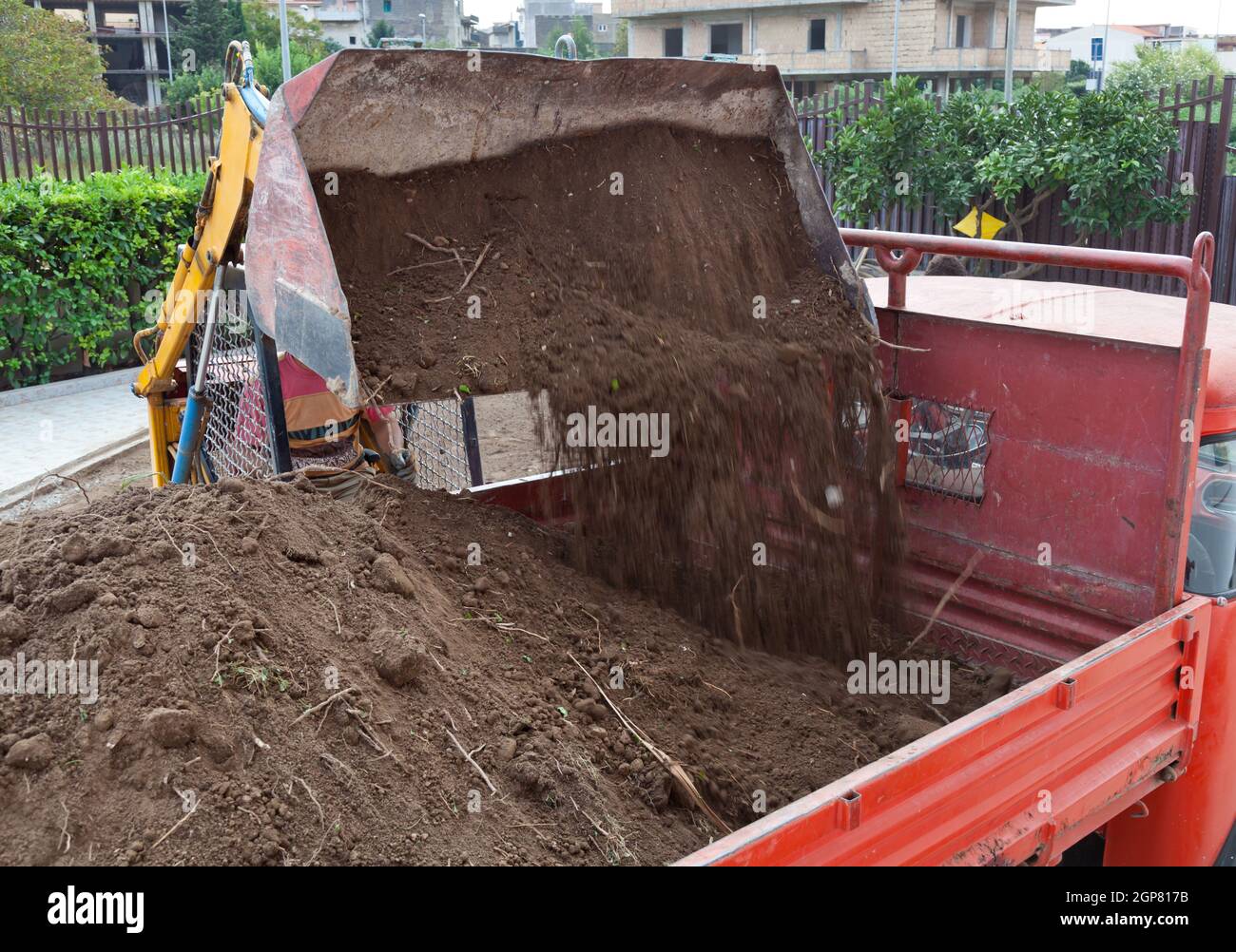 Excavator loading ground in truck tipper in the garden Stock Photo - Alamy