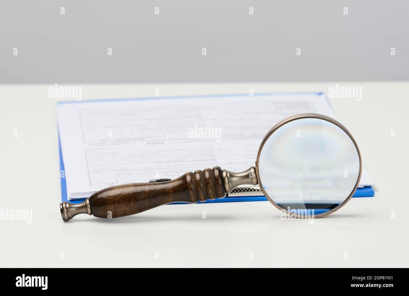 white paper sheets and a wooden magnifier on a white background, search ...