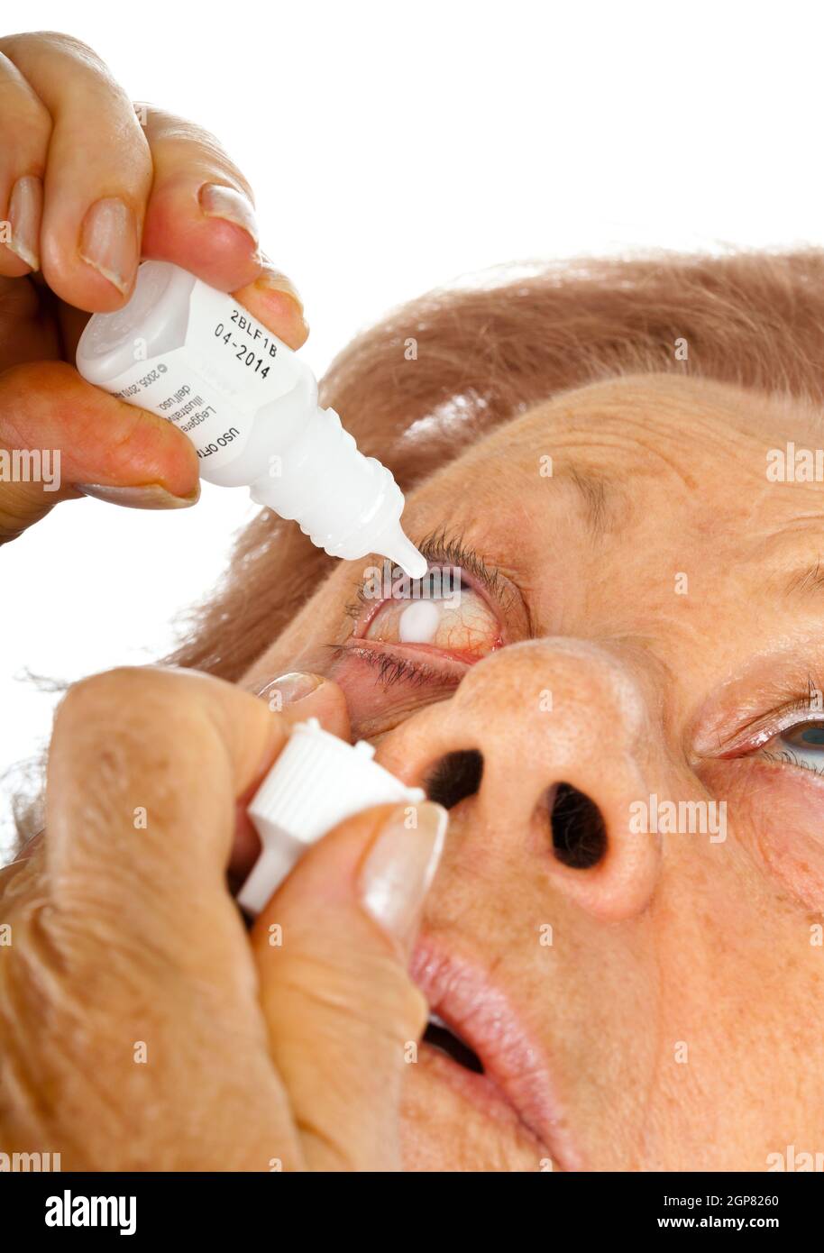 Elderly woman applying eye drops over white background Stock Photo - Alamy