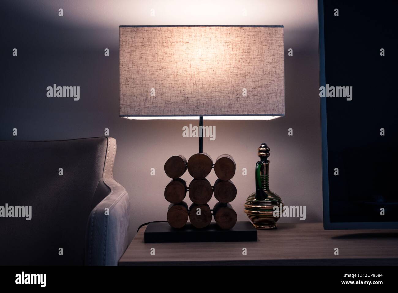 Side view of a nice desk lamp turned on in a dark room next to a sofa ...