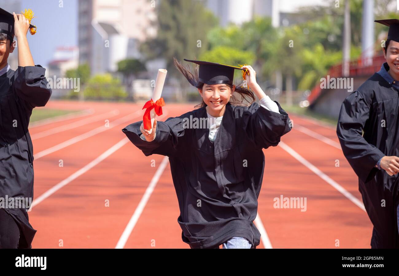 happy graduation students holding diploma and running on the stadium at ...