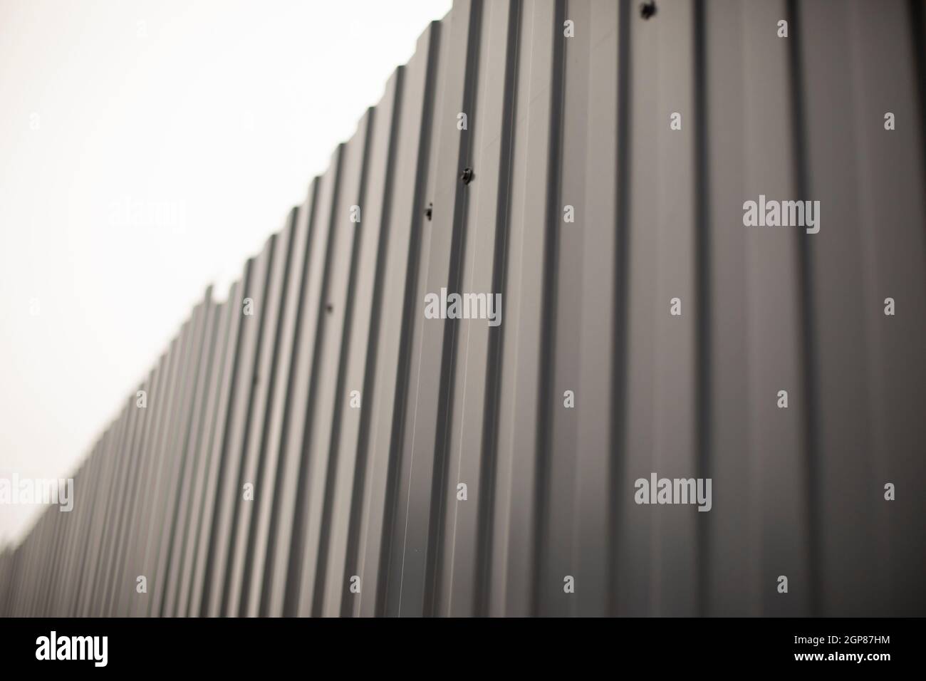 Grey fence made of metal. Solid high fence. Profiled metal is used in ...