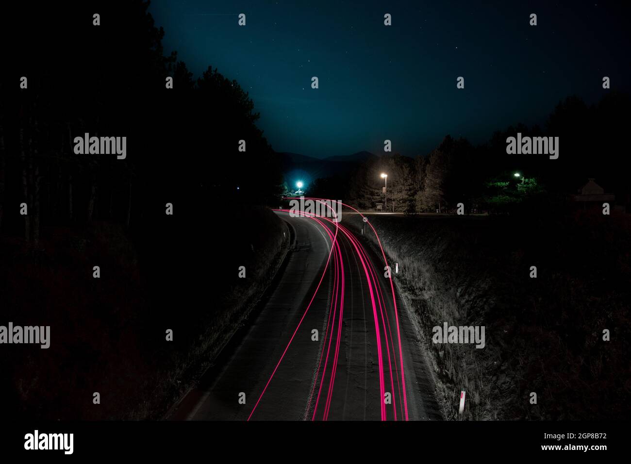 4 Red neon light trails on an empty mountain road with a starry night ...