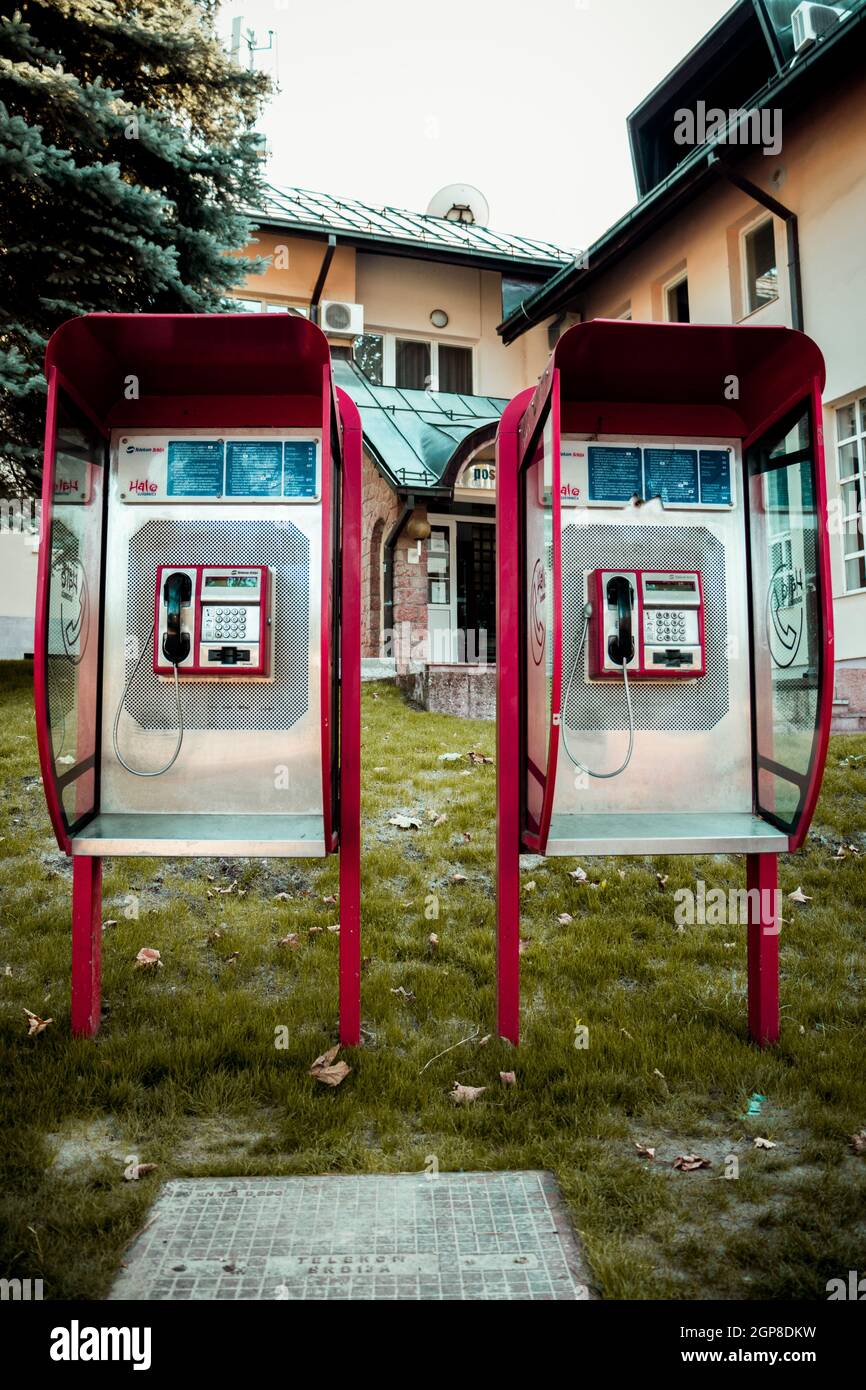Two telephone old red booths next to each other in front of a post ...