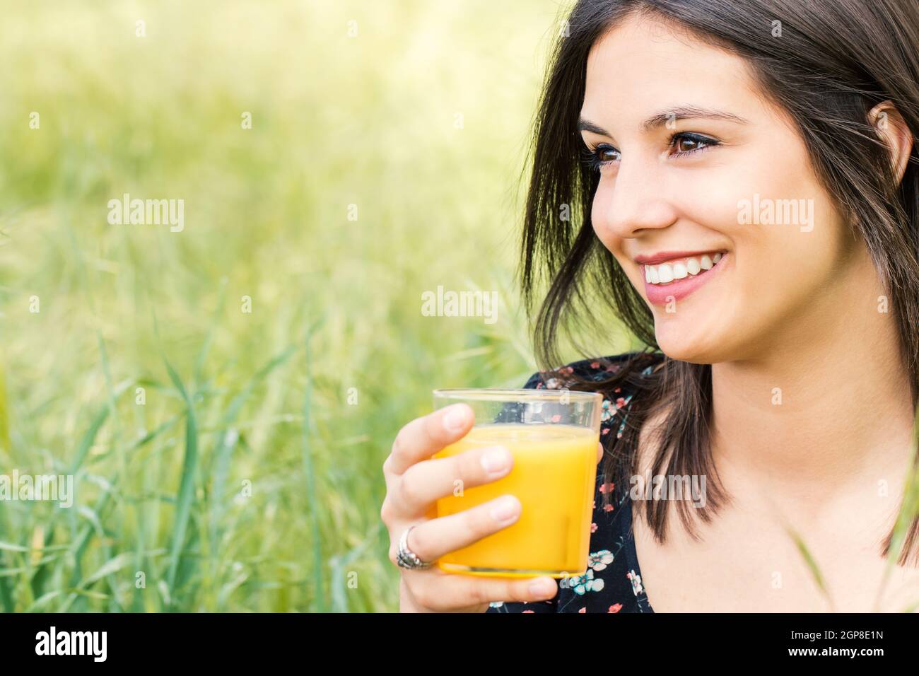 Close up face shot of cute young woman with charming smile drinking ...