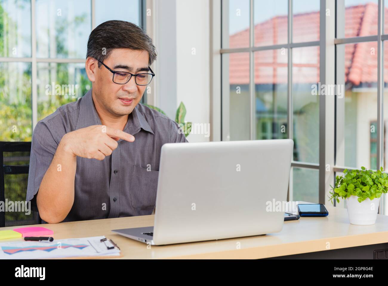 Asian senior business man working online on a modern laptop computer he ...