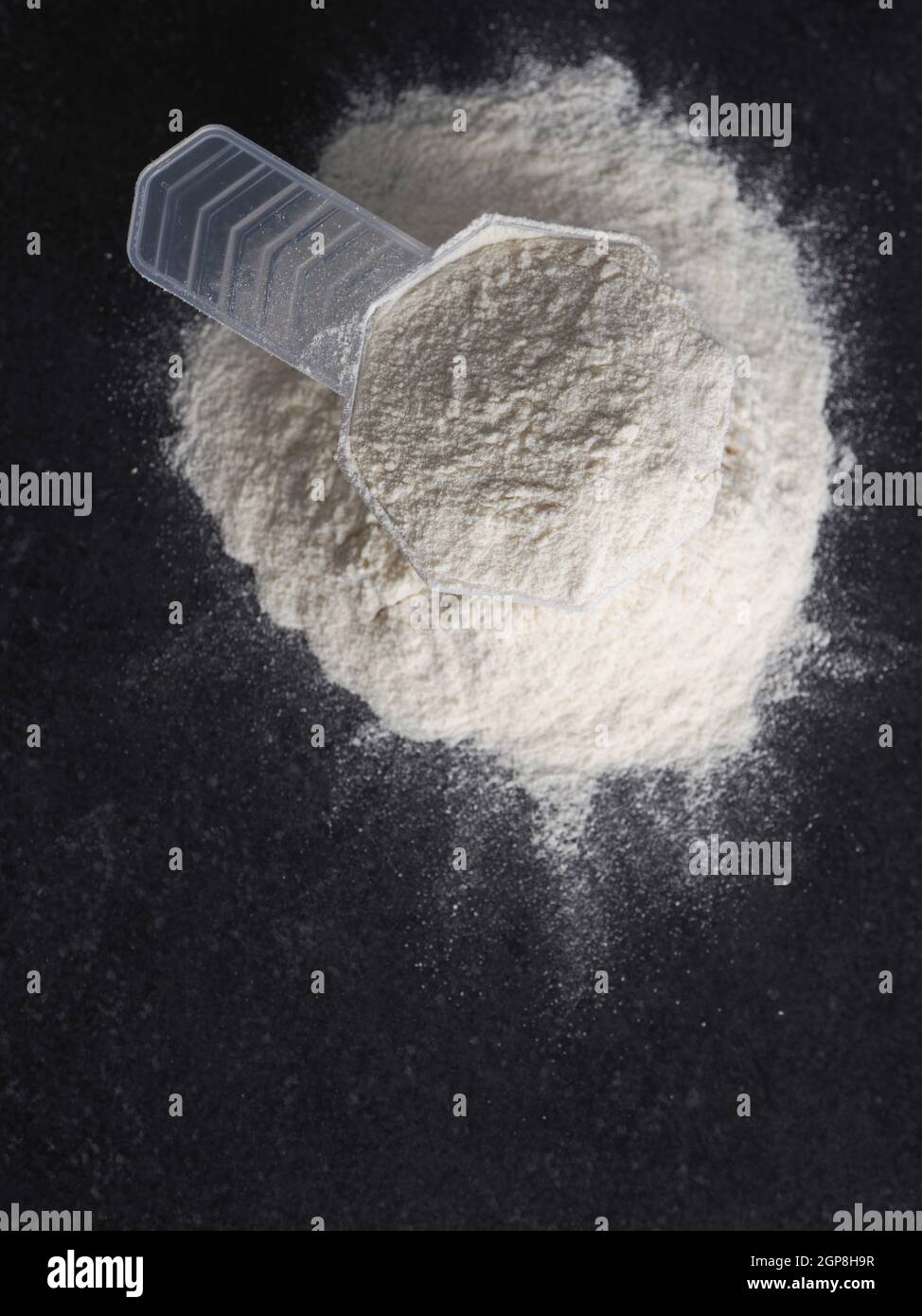 Measuring spoon with protein powder on a dark stone table with space ...