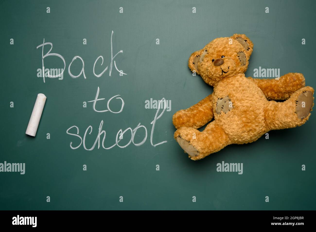 teddy bear and lettering back to school in white chalk on a green ...