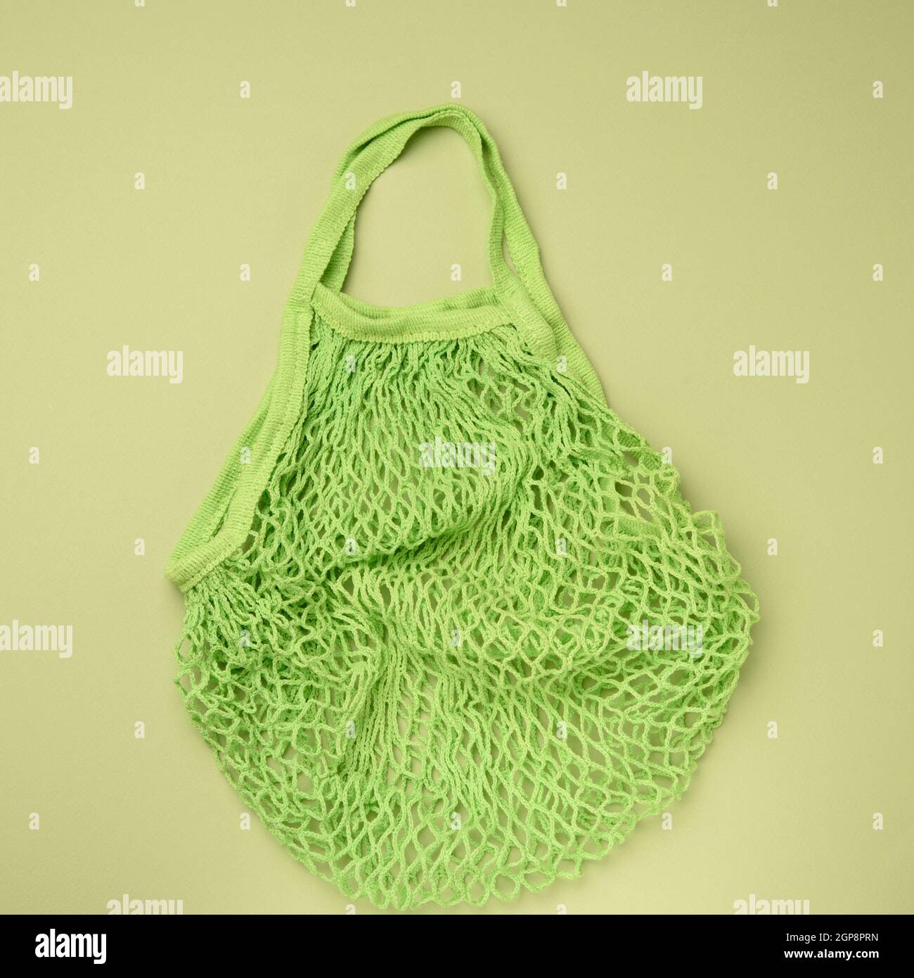 empty green reusable string bag woven from thread on a green background ...