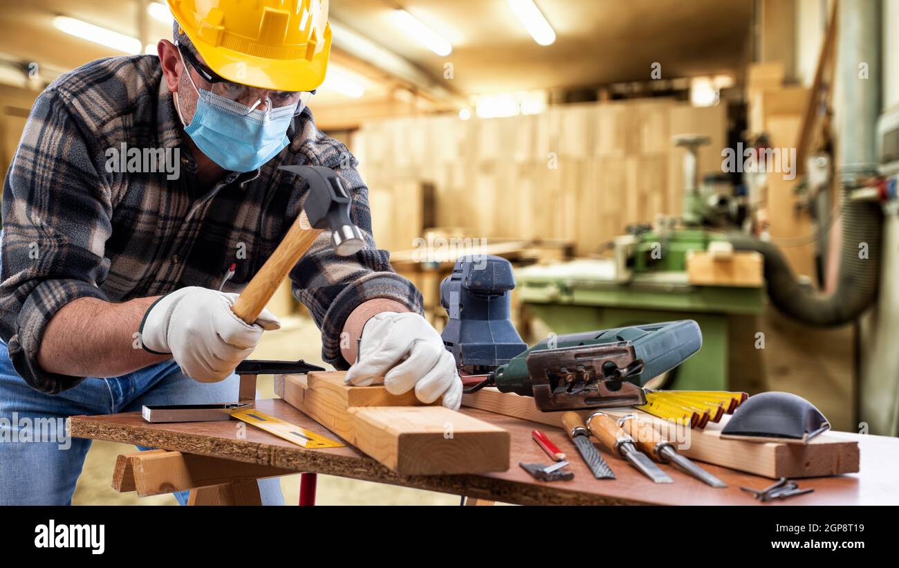 Carpenter worker at work in the carpentry workshop, wears helmet ...