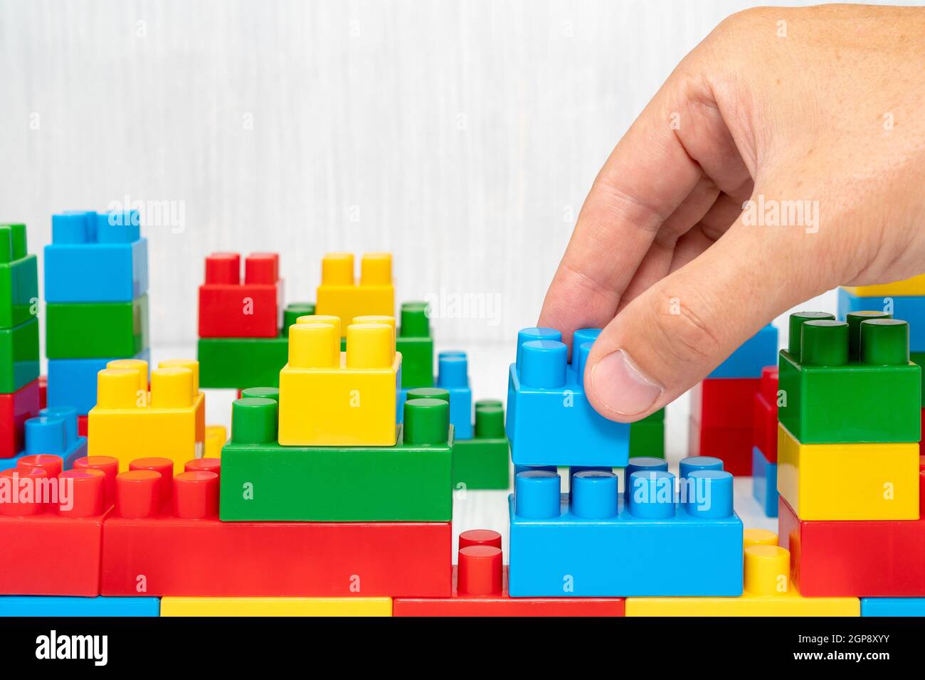 Hand building up a wall by stacking up block Stock Photo - Alamy