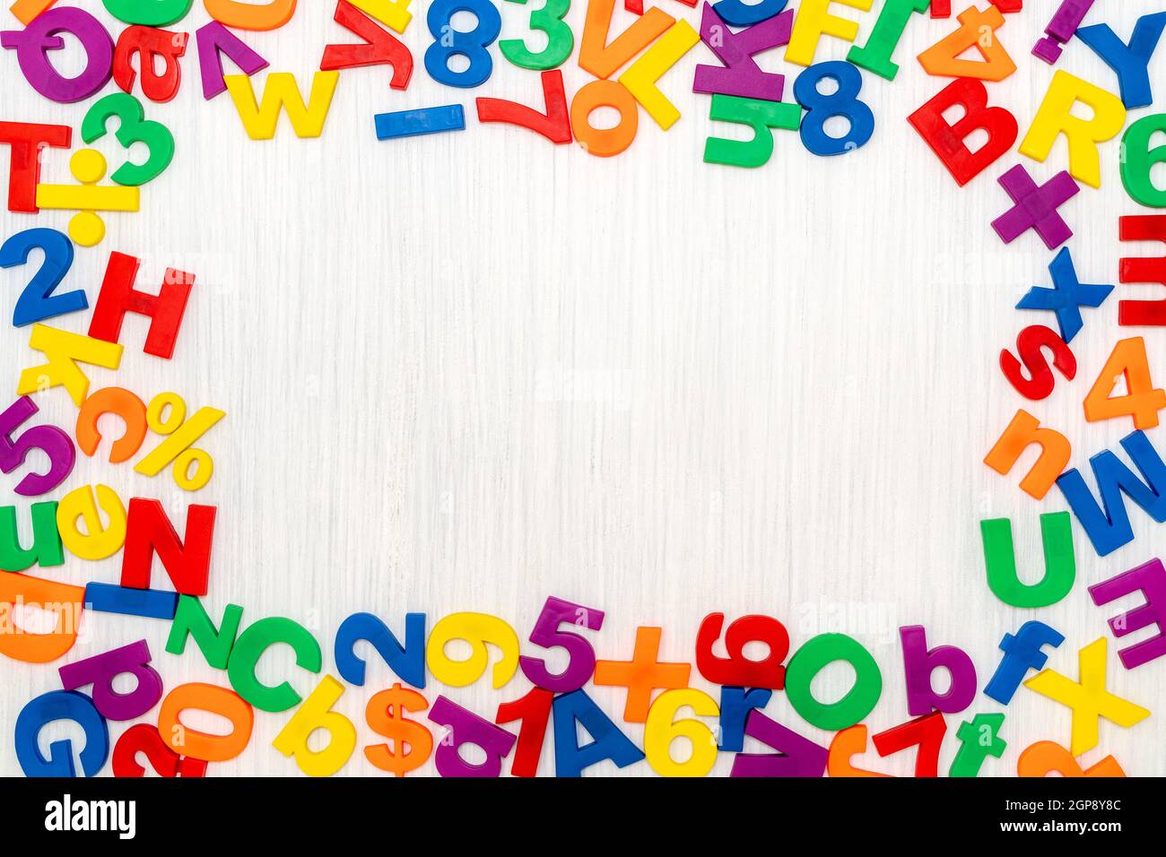 Colorful plastic numbers and letters as frame on a wooden background ...