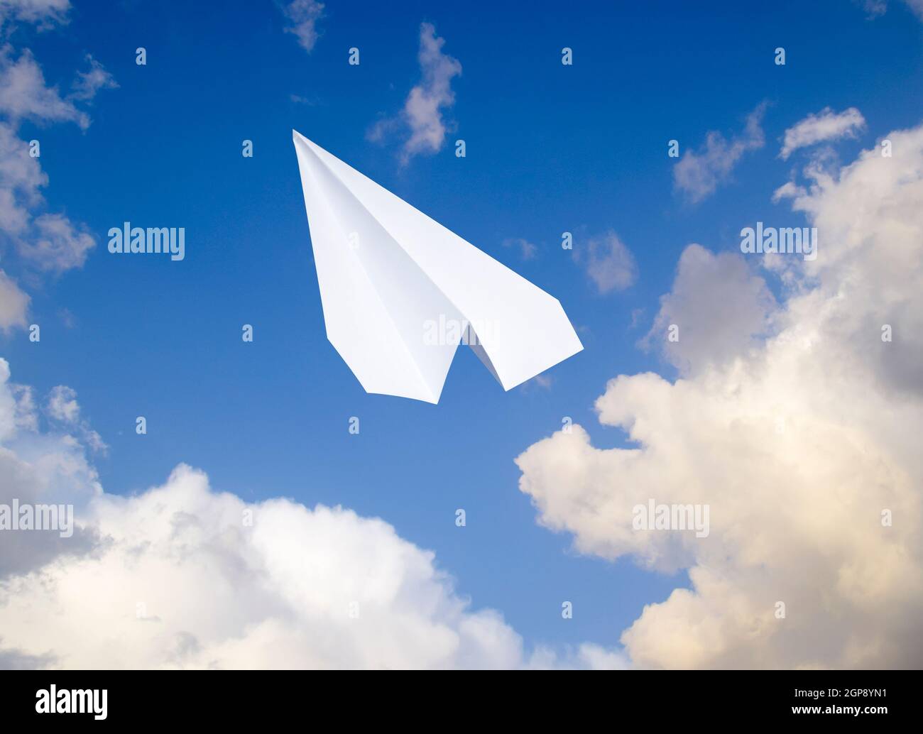 White paper airplane in a blue sky with clouds. The message symbol in ...
