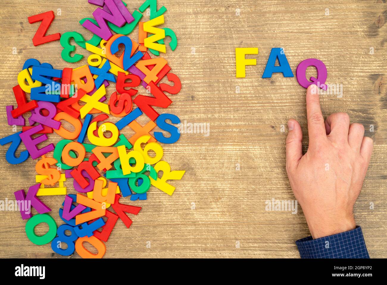 Hand arrange plastic letters as FAQ abbreviation ( frequently asked ...