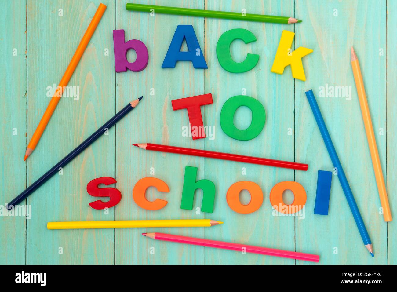Sentence BACK TO SCHOOL with a colorful pencils on wood background ...