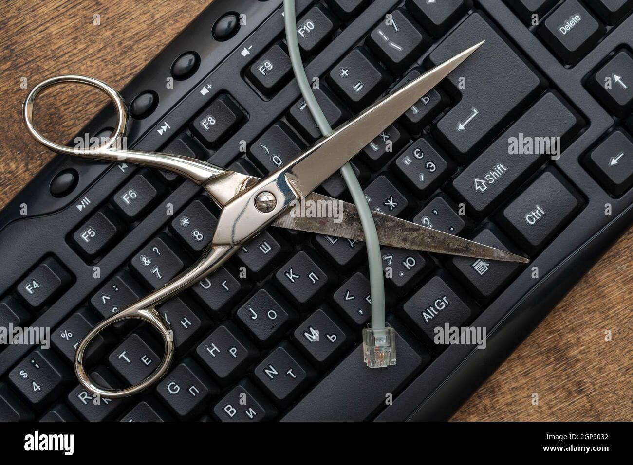 Scissor cutting internet cable over computer keyboard. Prevention of ...
