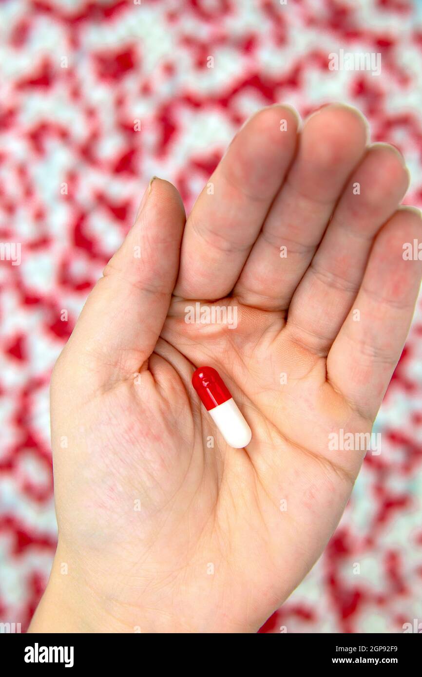 hands holding red and white capsules for medication, vitamin or drugs ...
