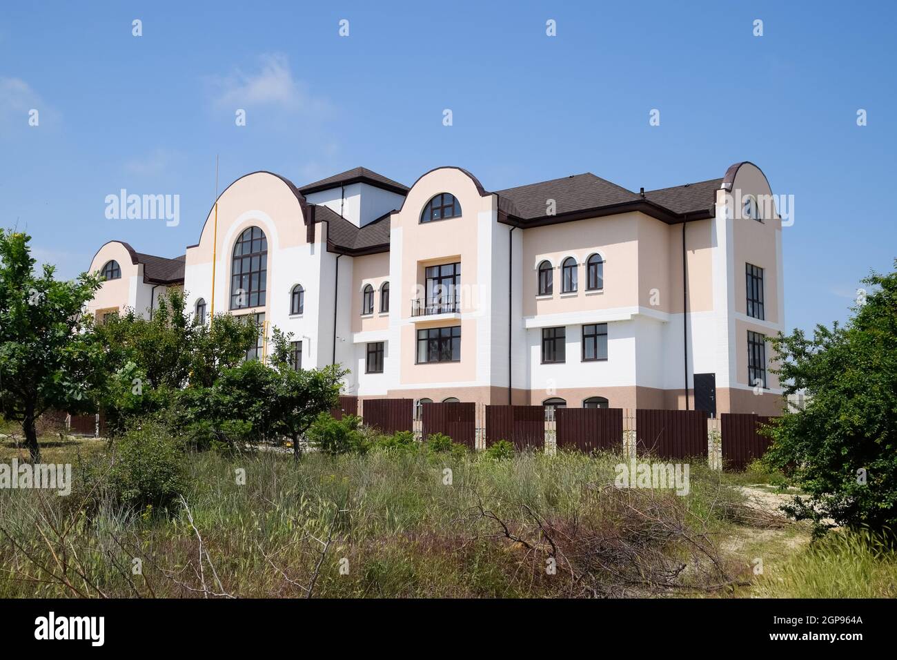 Three-story hotel mansion with a brown metal fence Stock Photo - Alamy