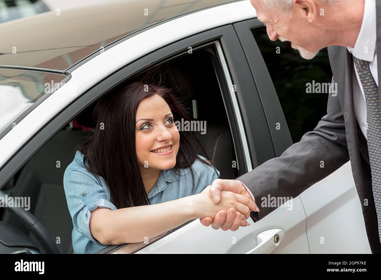 Happy customer and car salesman shaking hands Stock Photo - Alamy