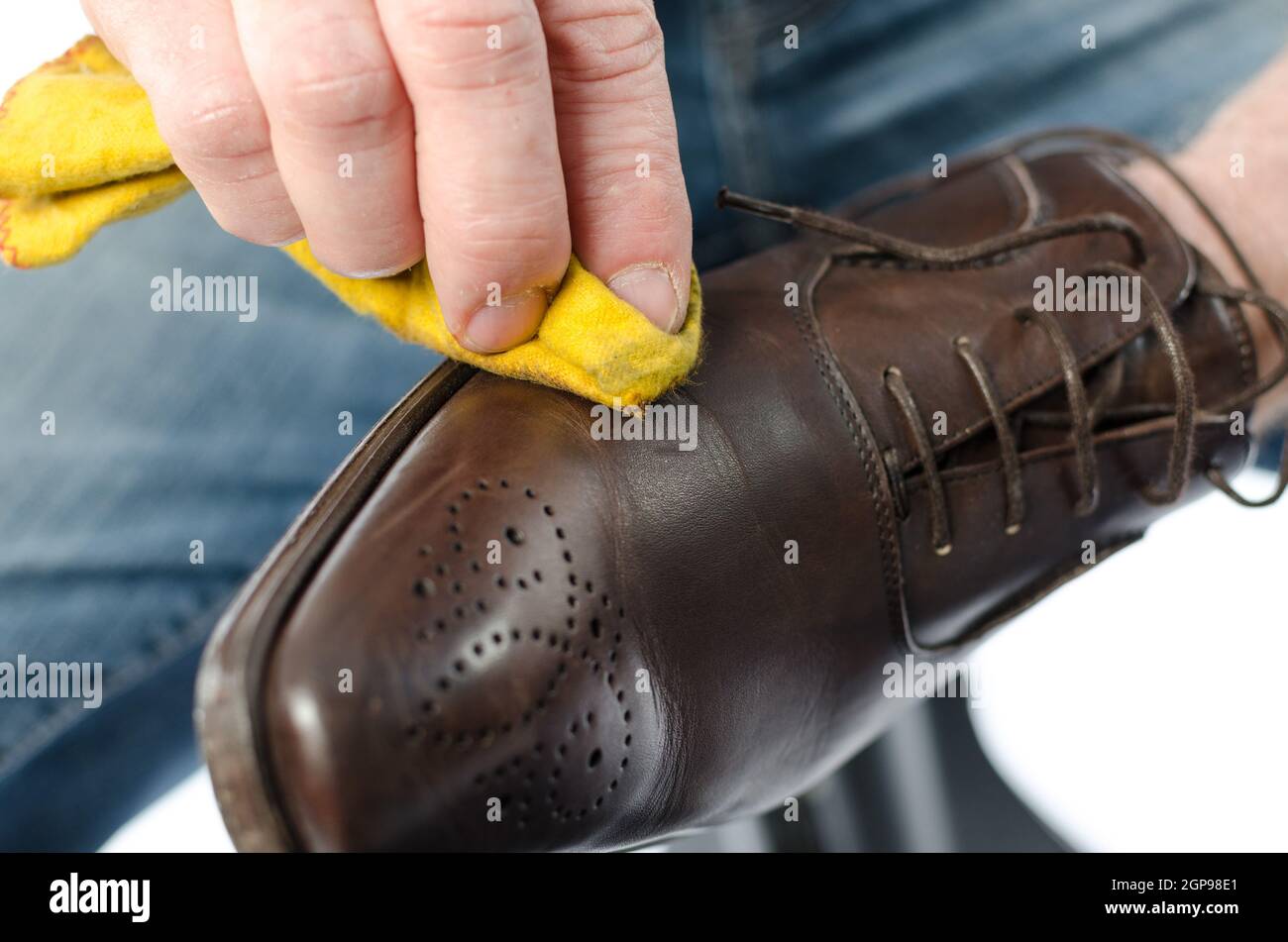 Shoe shiner shining a brown shoe with a yellow rag Stock Photo - Alamy