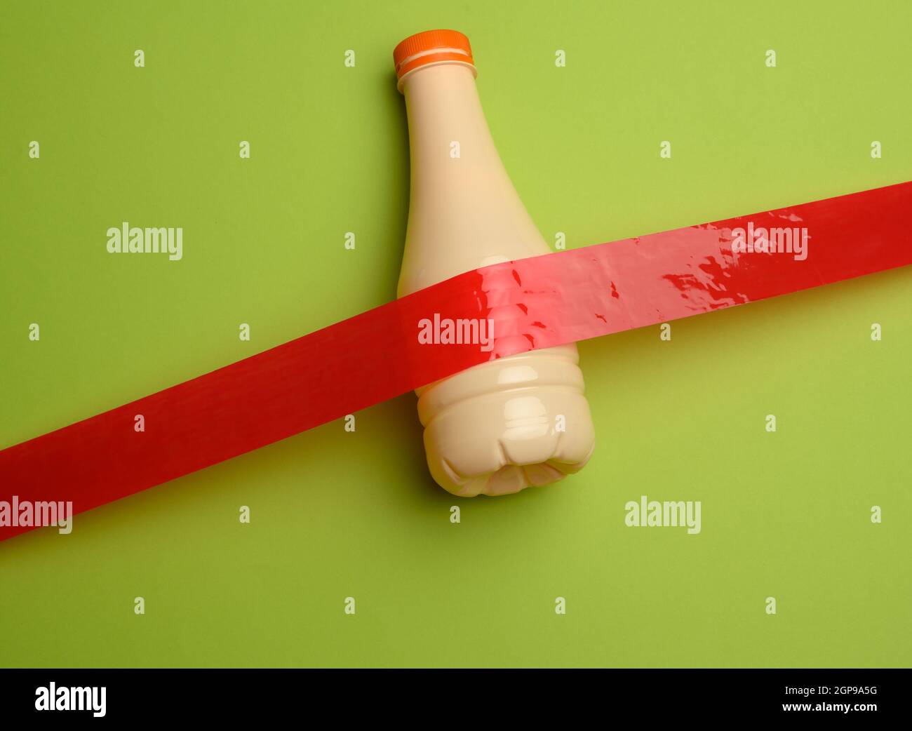 plastic beige bottle for dairy products glued with red tape on green ...