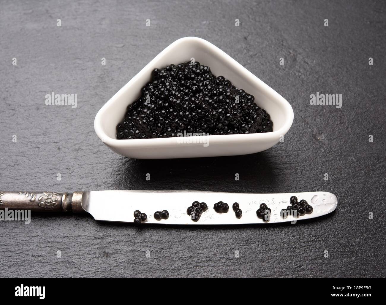 black grainy caviar of paddlefish fish in a white ceramic bowl, black ...