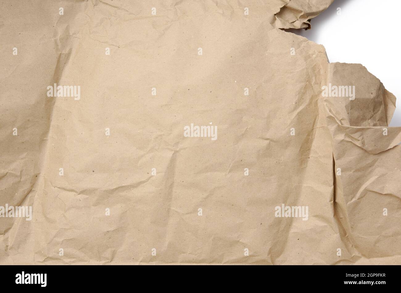large piece of crumpled brown paper with torn edge isolated on white ...