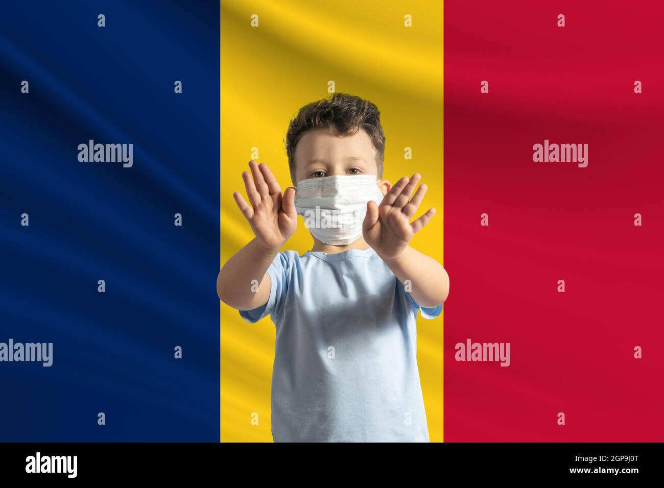 Little white boy in a protective mask on the background of the flag of ...