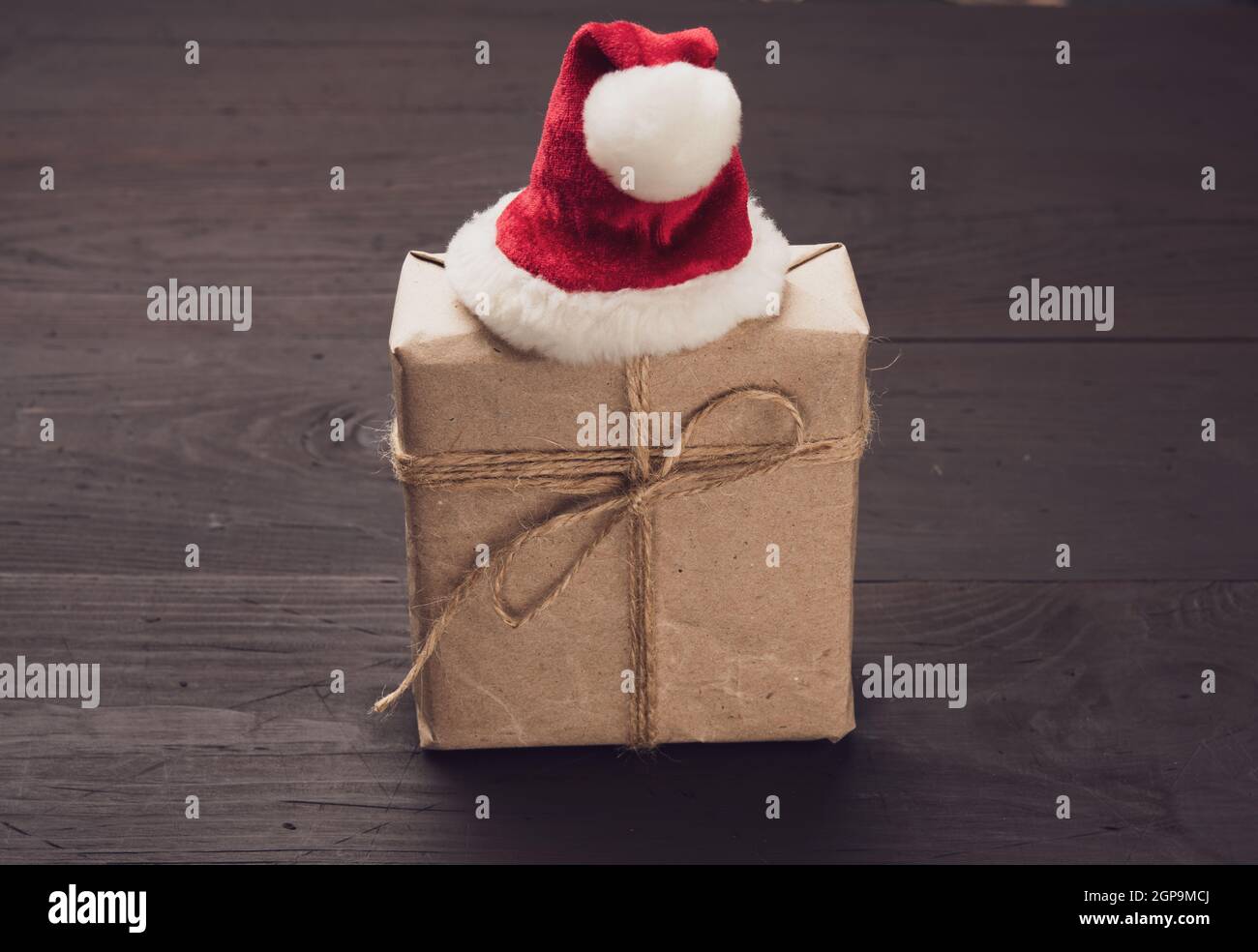 box wrapped in brown kraft paper and red hat, gift on a wooden ...