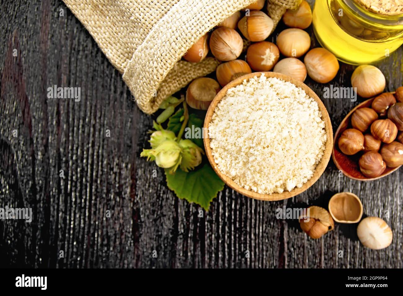 Hazelnut flour in a bowl, nuts in bag, a spoon, oil in glass jar and ...