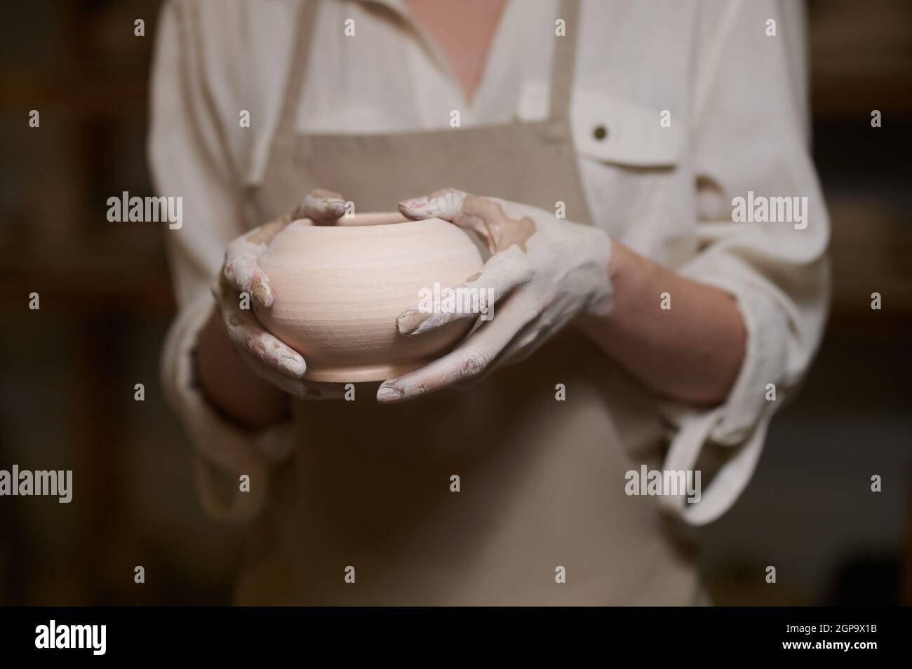 A female potter in her workshop looking involved in the process of ...