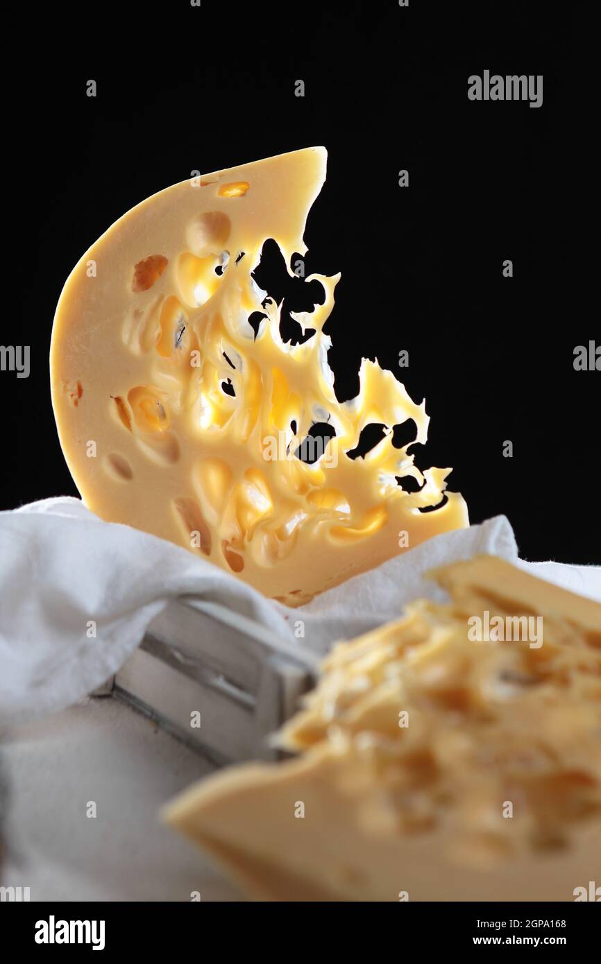 Large chunks of hard maasdam cheese on a black background. Cheese with ...