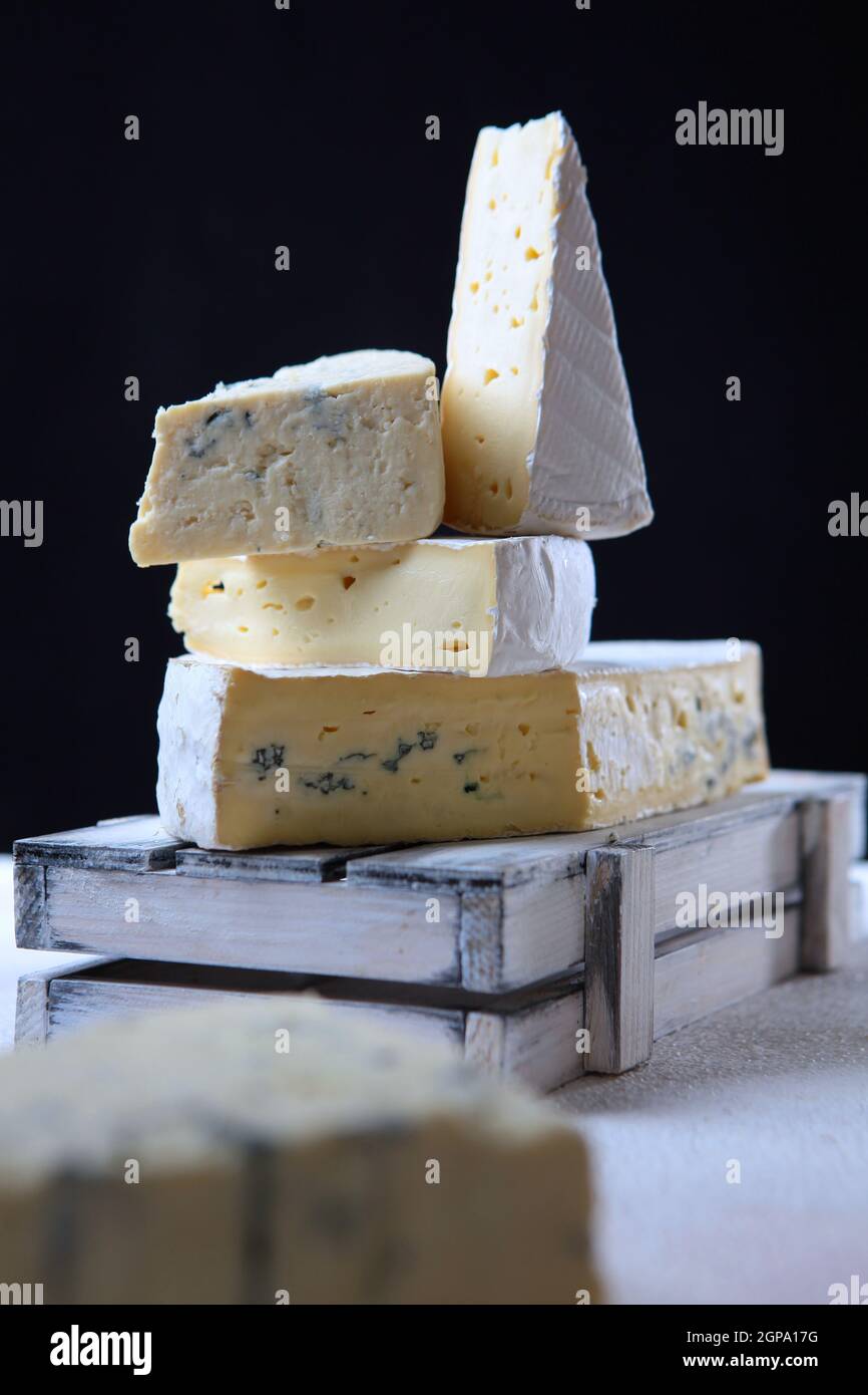 Soft white cheese with blue mold in a white wooden box on a black ...