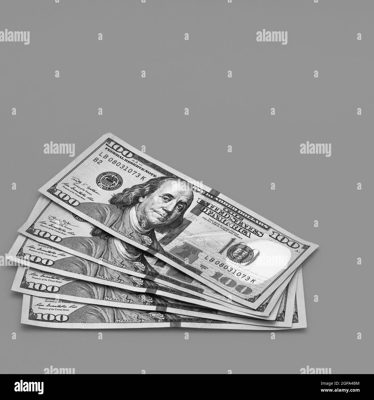 A wad of hundred-dollar cash fanned out on a gray background. A place ...