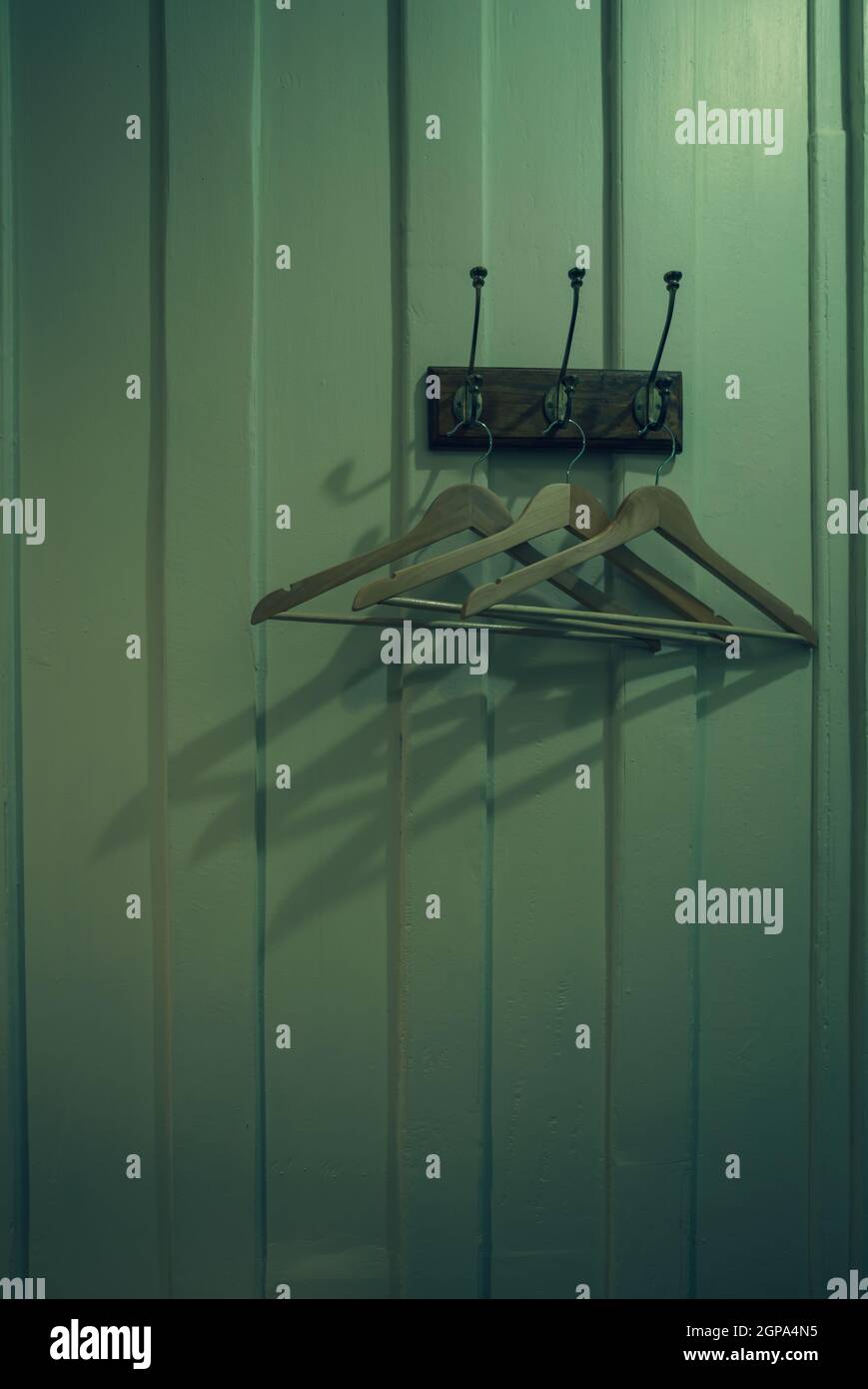 Brown wooden cloth hanger with shadow hanging on metal hook on wooden ...