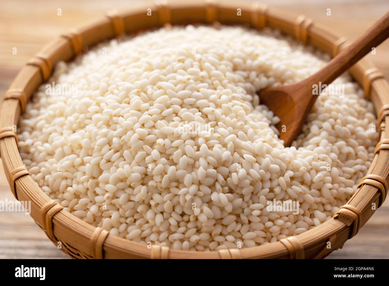 Glutinous rice in a bamboo colander set against a background of trees ...