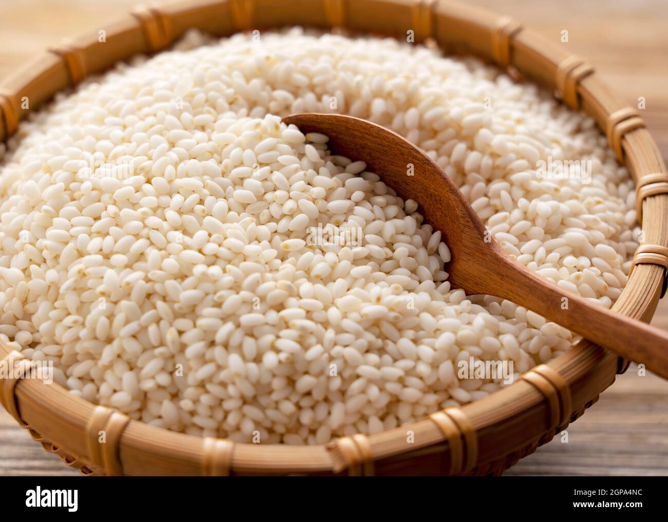 Glutinous rice in a bamboo colander set against a background of trees ...