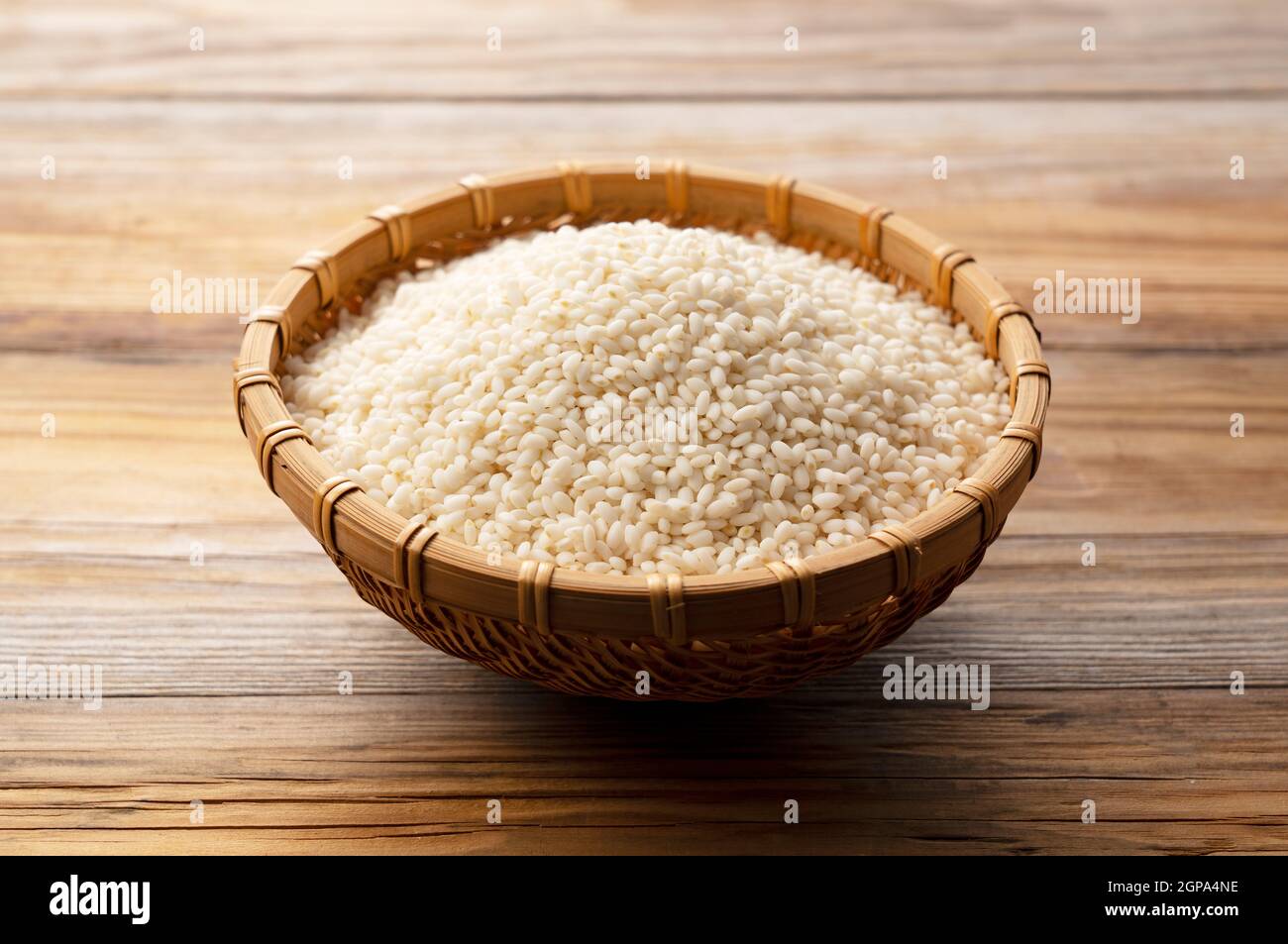 Glutinous rice in a bamboo colander set against a background of trees ...