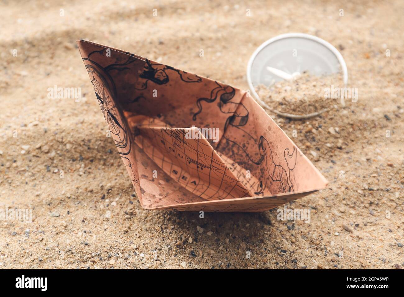 Paper boat and compass on sand, closeup Stock Photo - Alamy
