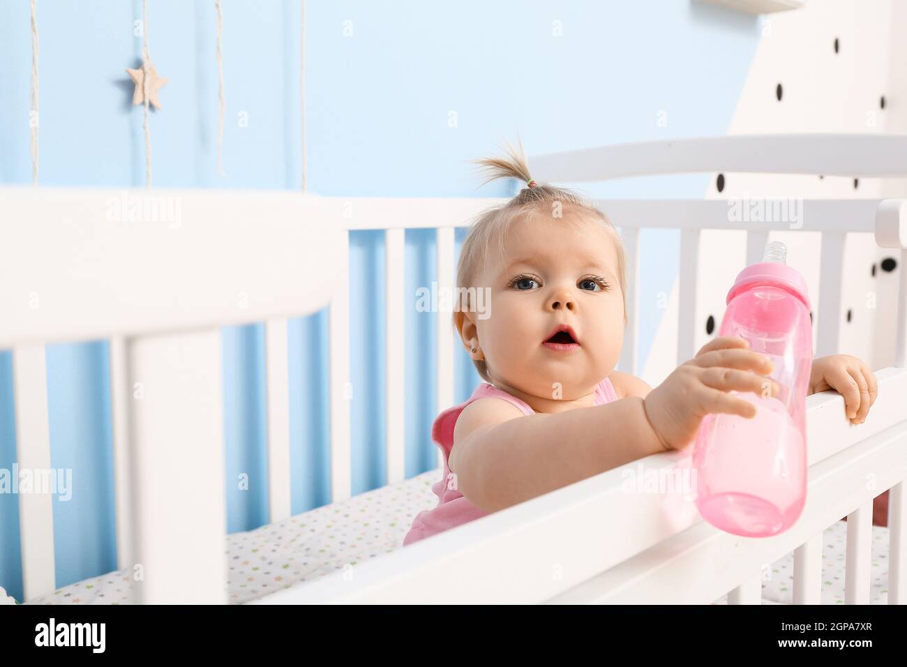 Cute baby girl with bottle of water in cot Stock Photo - Alamy