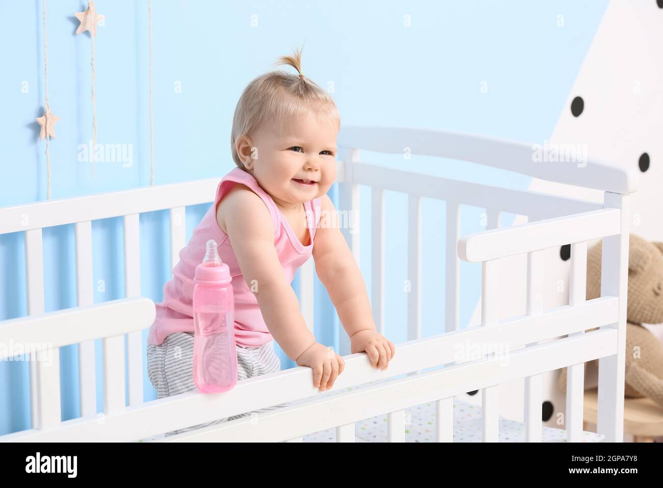 Cute baby girl with bottle of water in cot Stock Photo - Alamy