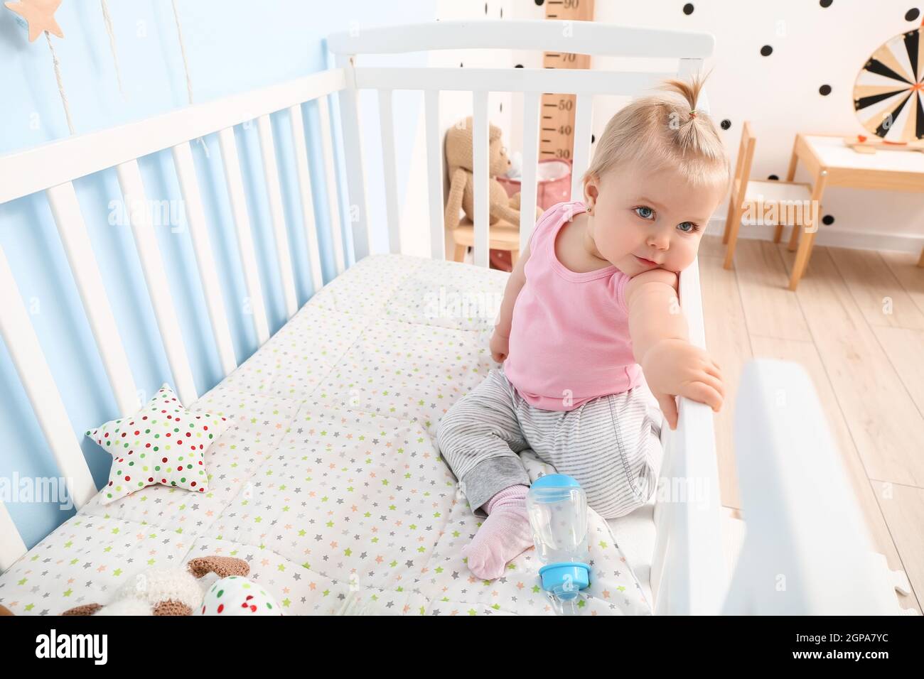 Cute baby girl with bottle of water in cot Stock Photo - Alamy