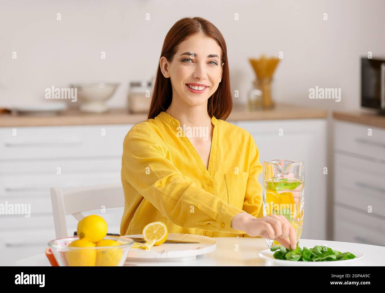 Beautiful young woman making fresh lemonade at home Stock Photo - Alamy