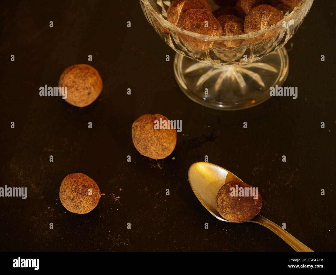 Several Chocolate Truffles with cocoa powder with a spoon on black ...
