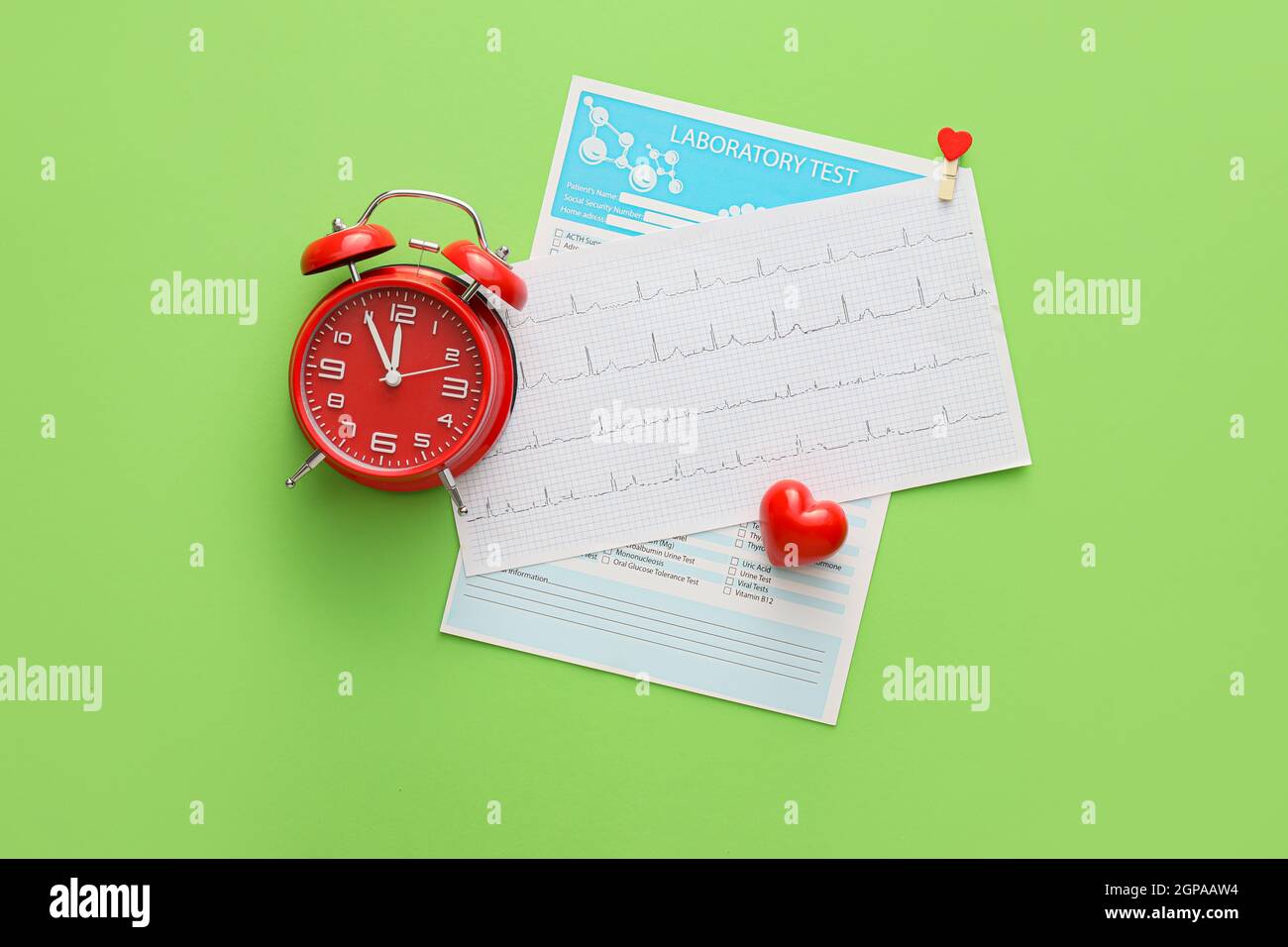 Red alarm clock with cardiogram and laboratory test on green background ...