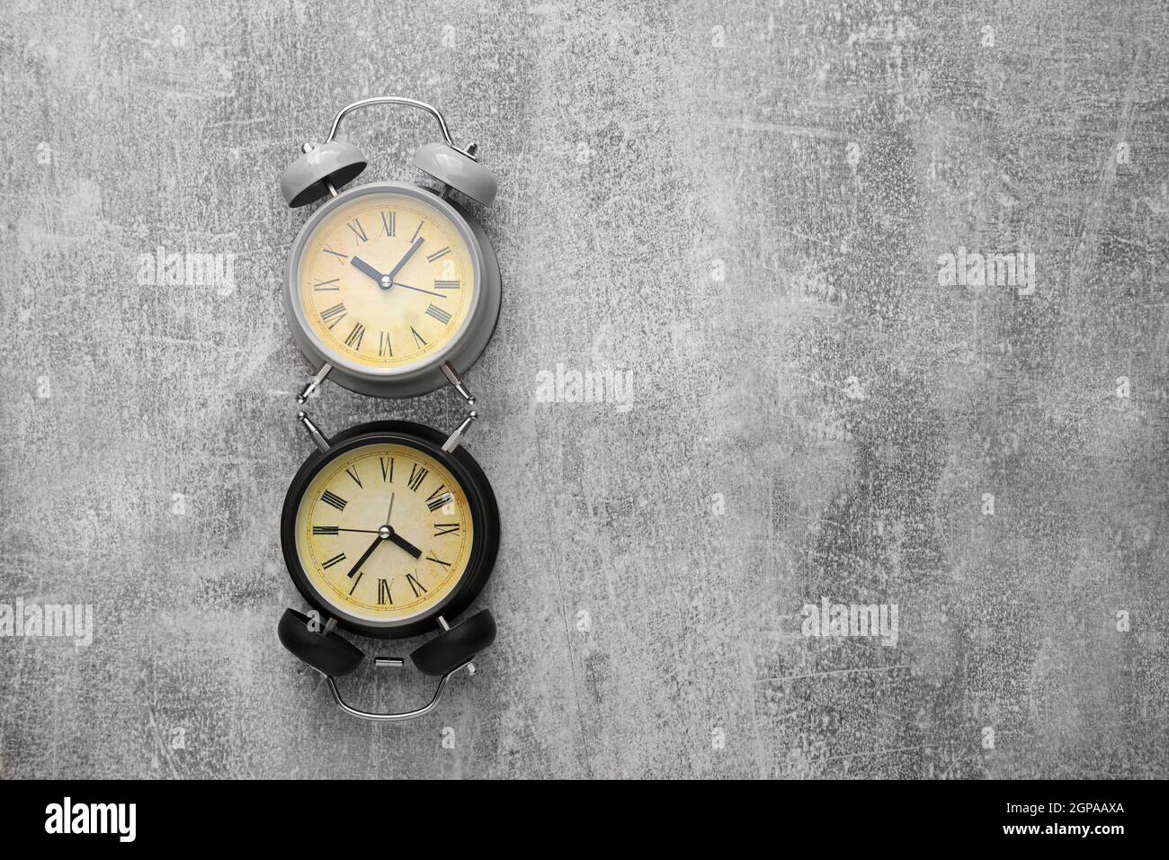 Two old style alarm clocks on textured grey background Stock Photo - Alamy
