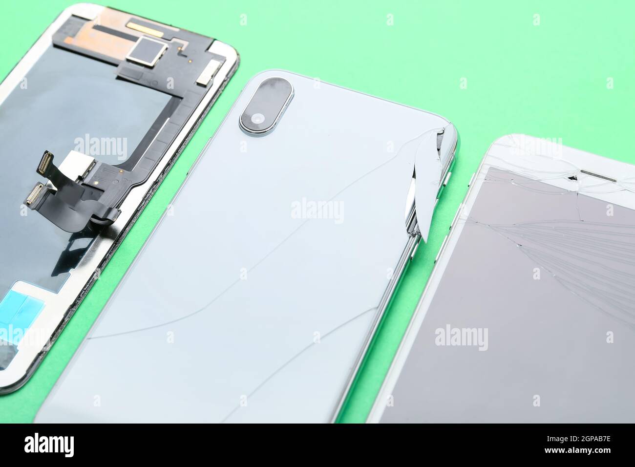 Broken mobile phones and display module on green background, closeup ...