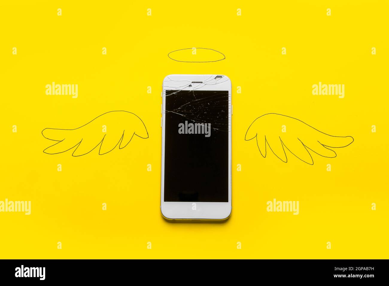 Damaged mobile phone and drawn angel wings with nimbus on yellow ...