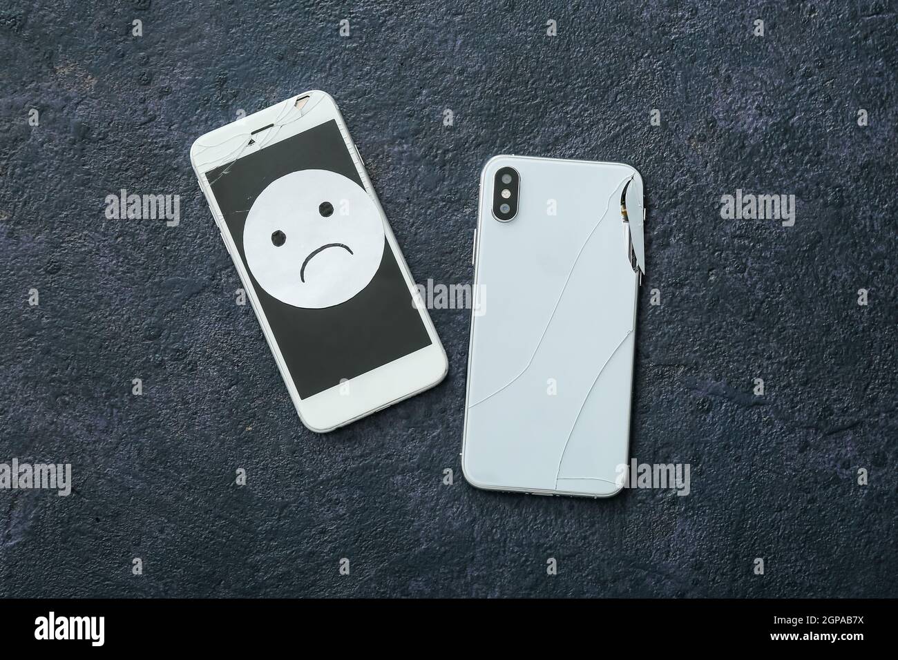 Damaged mobile phones and sad smile on dark background Stock Photo - Alamy