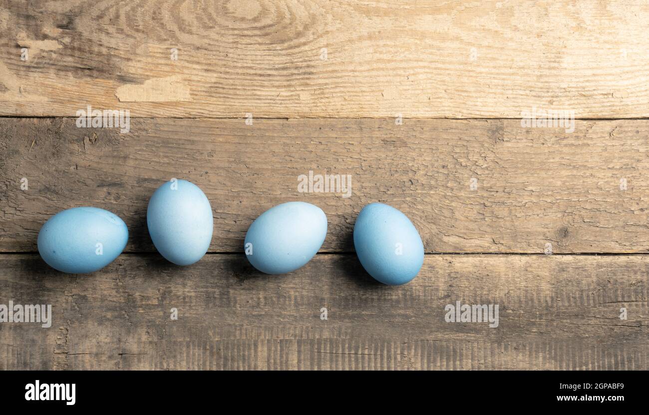 Naturally colored organic eggs in a row on a rustic table with space ...
